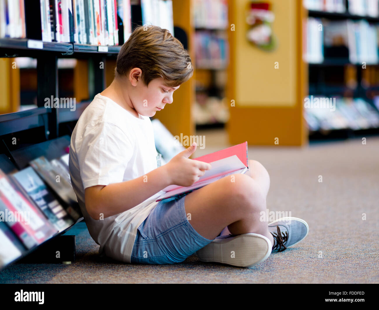 Boy in library with books Stock Photo - Alamy