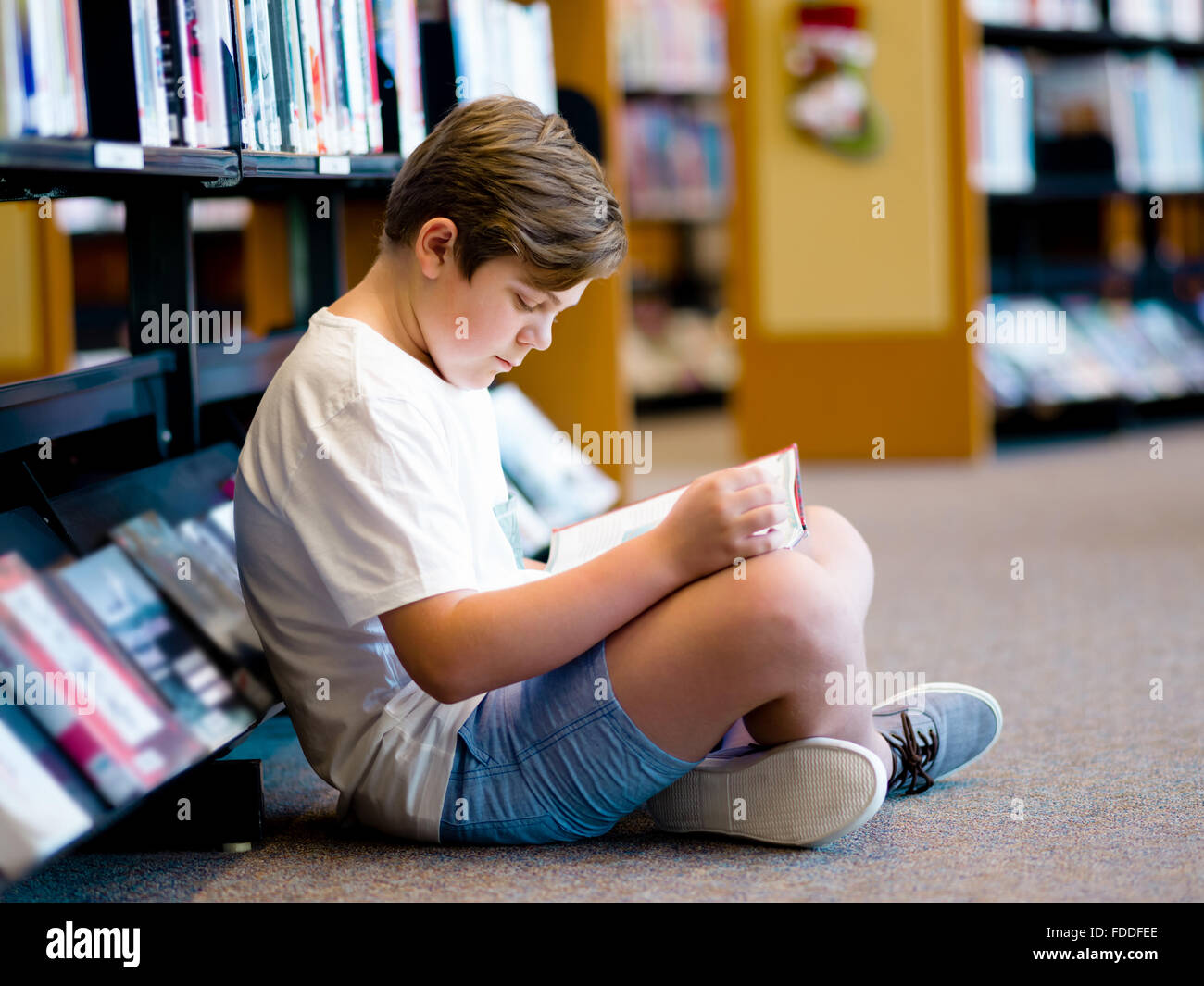 Boy in library with books Stock Photo - Alamy