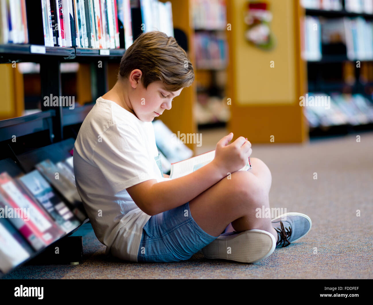 Boy in library with books Stock Photo - Alamy