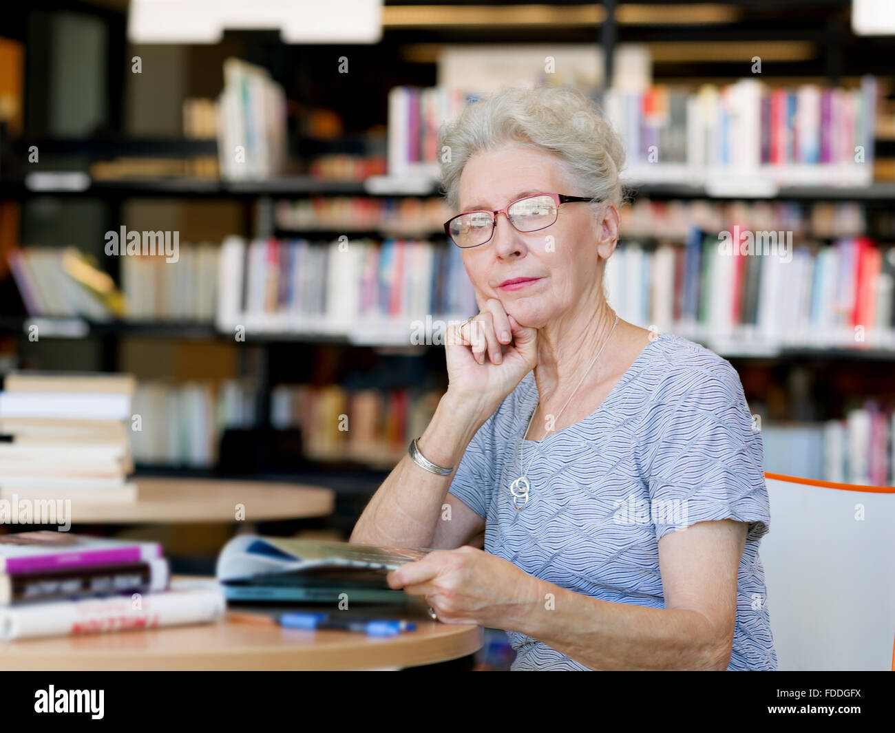 Elderly lady reading books in library Stock Photo - Alamy