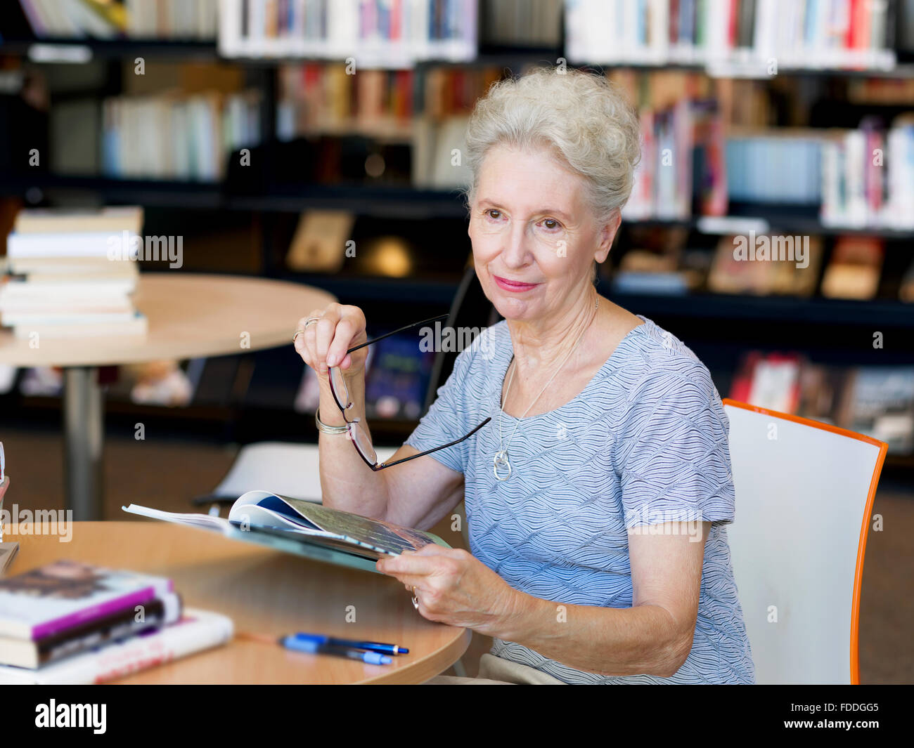 Elderly lady reading books in library Stock Photo - Alamy