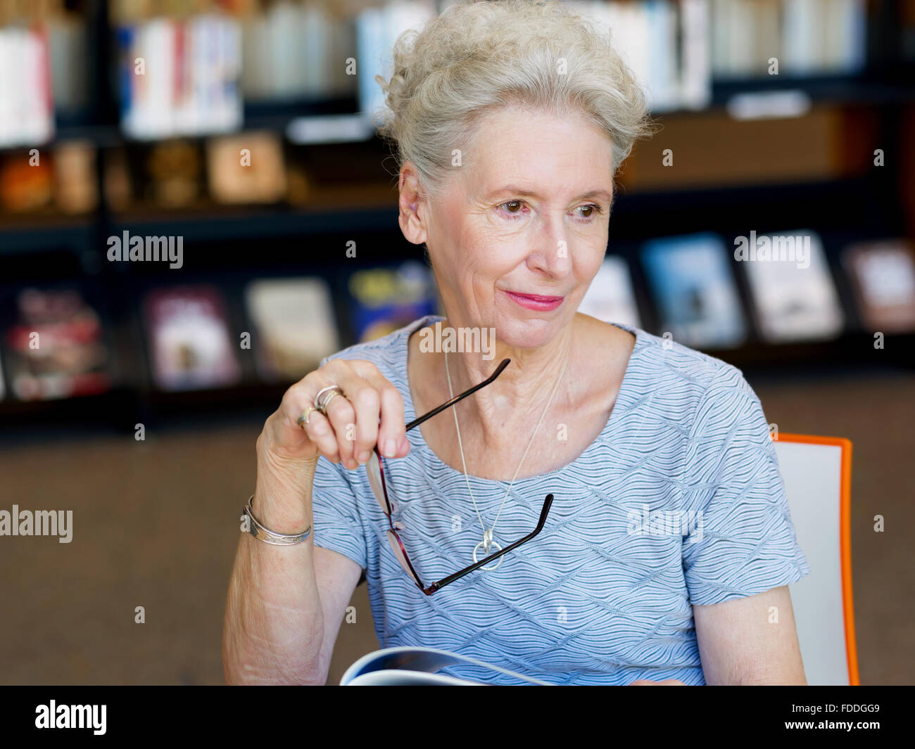 Elderly lady reading books in library Stock Photo - Alamy