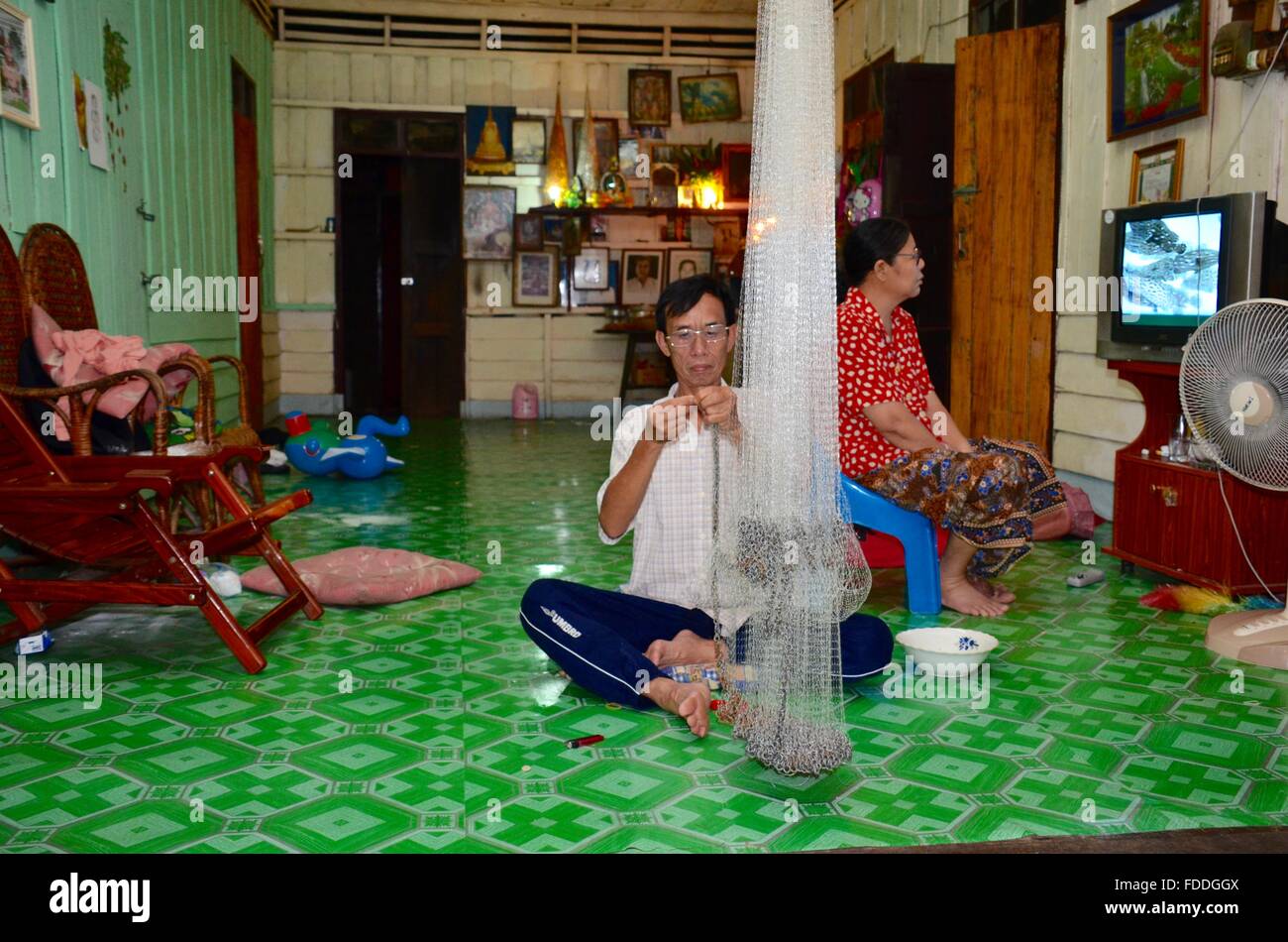 Fisherman Repairing the nets as she's watching fish on TV Stock Photo ...