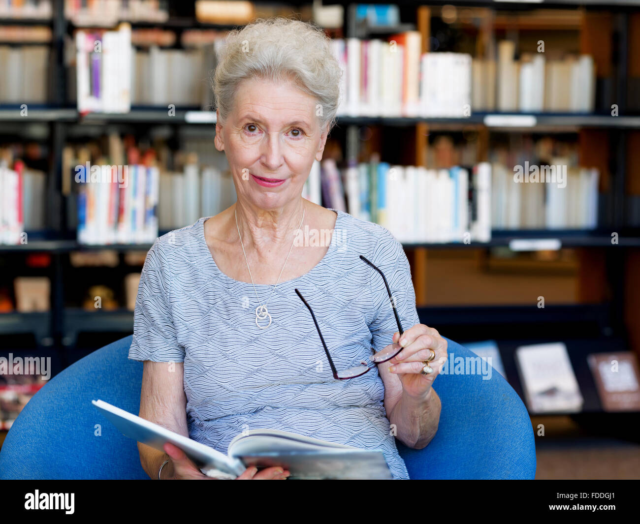 Elderly lady reading books in library Stock Photo - Alamy