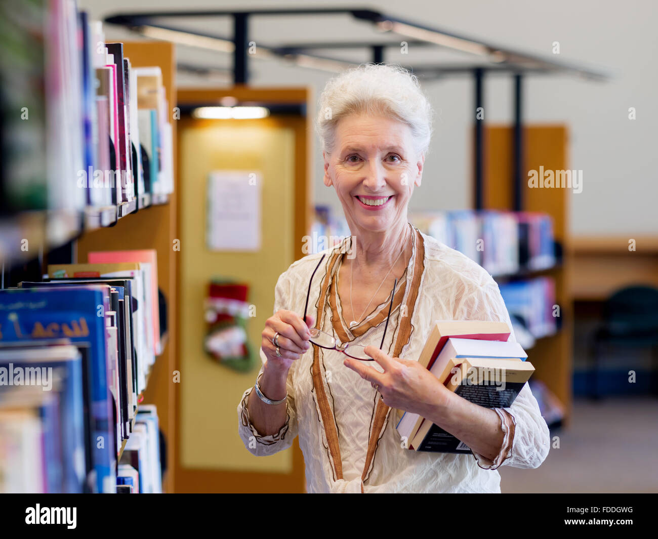 Elderly lady standing next to book shelves in library Stock Photo - Alamy