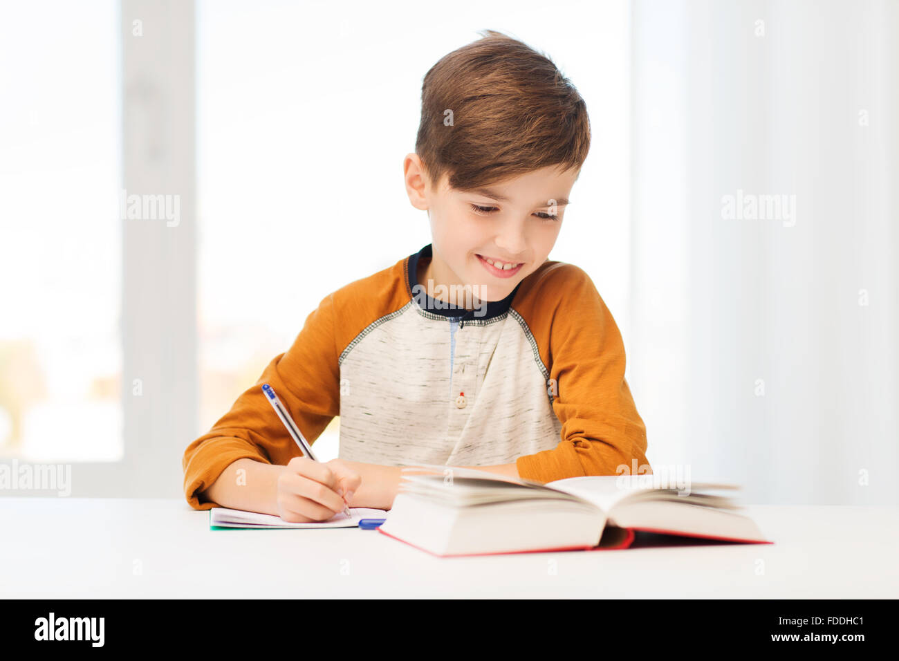 smiling student boy writing to notebook at home Stock Photo - Alamy