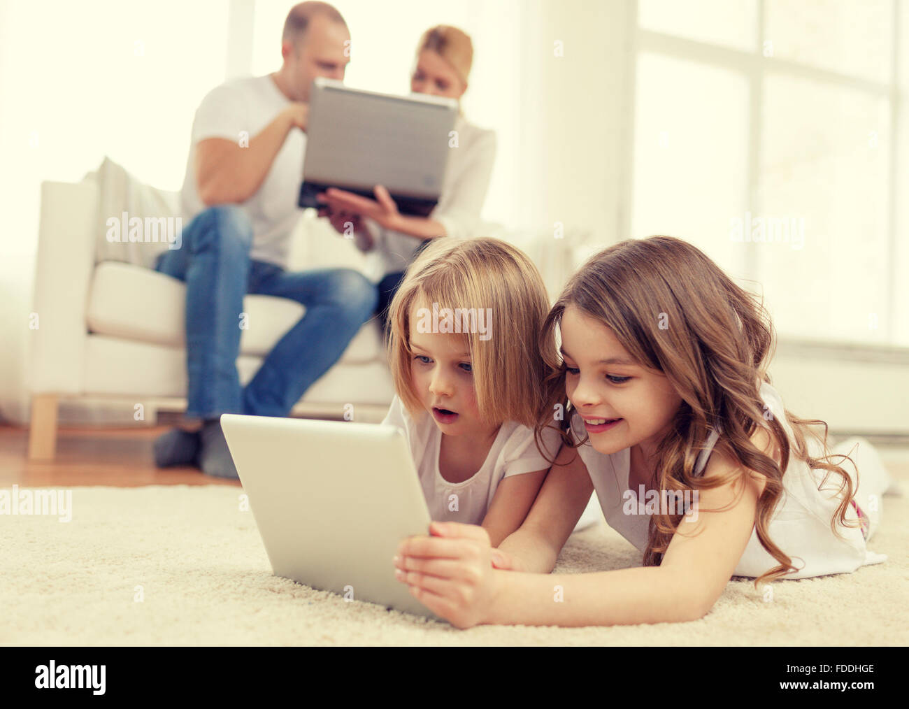 smiling sister with tablet pc and parents on back Stock Photo - Alamy