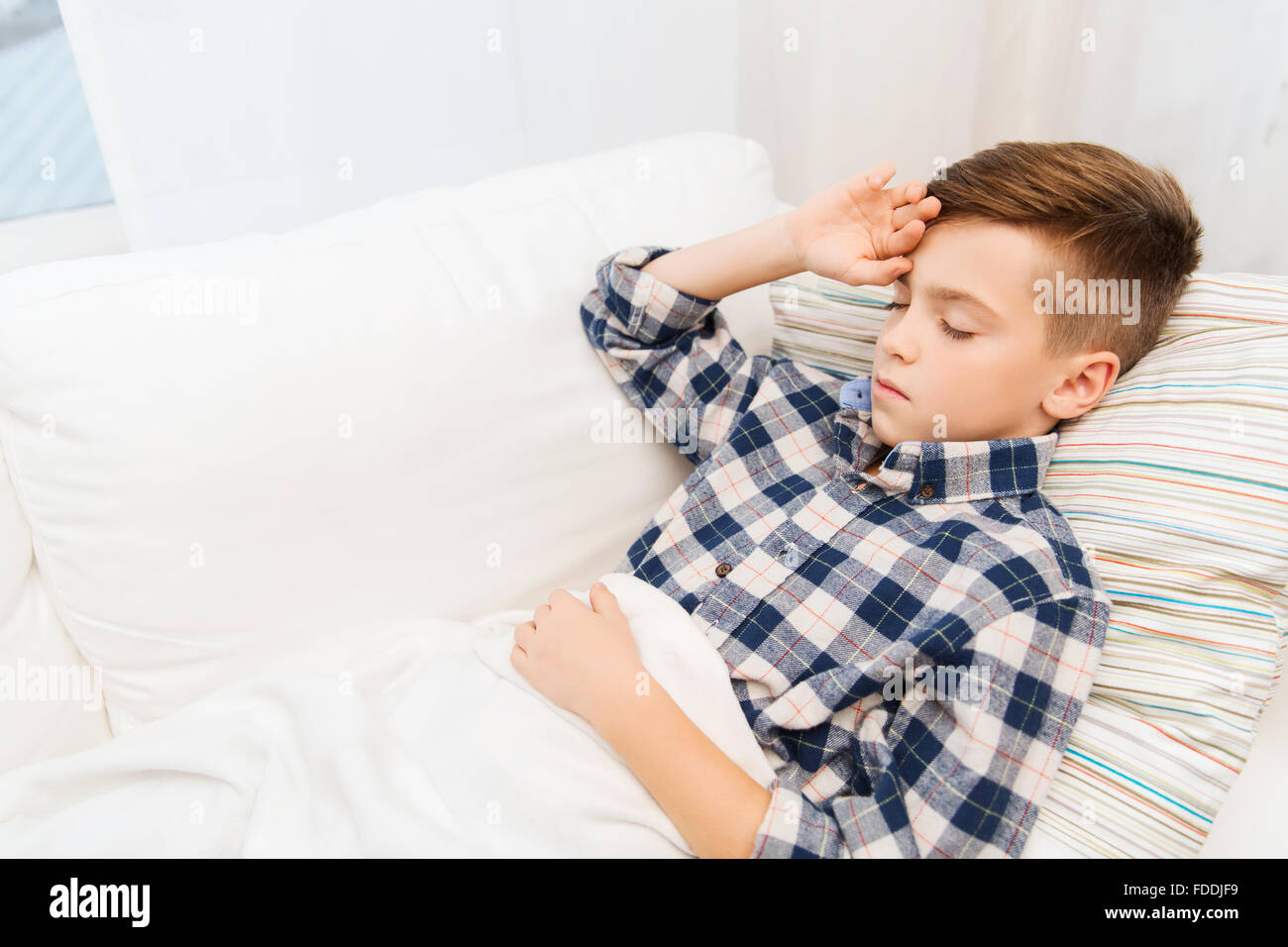 ill boy lying in bed and suffering from headache Stock Photo - Alamy