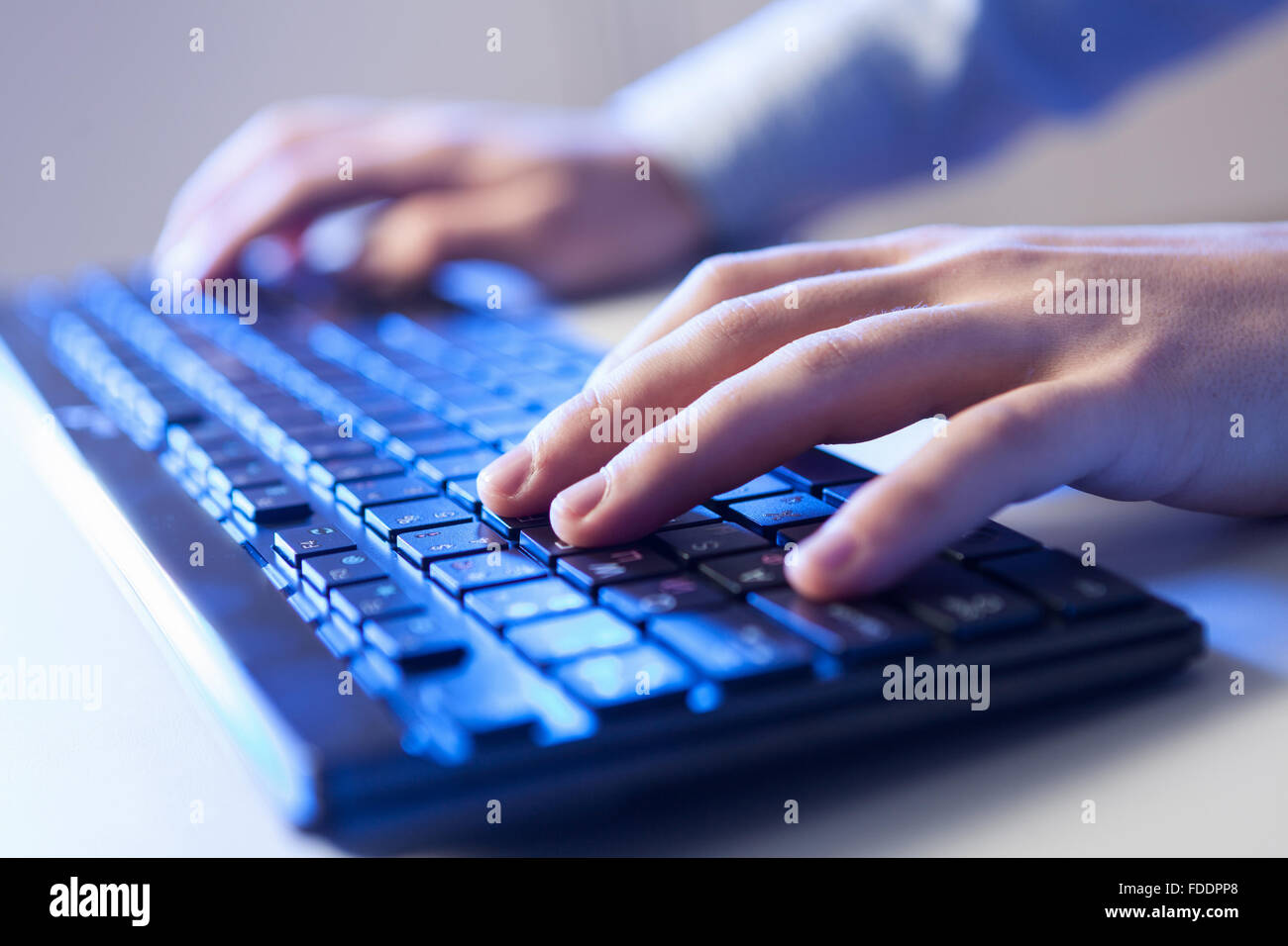 Click! Hands of a man on a keyboard with blue backlighting Stock Photo ...