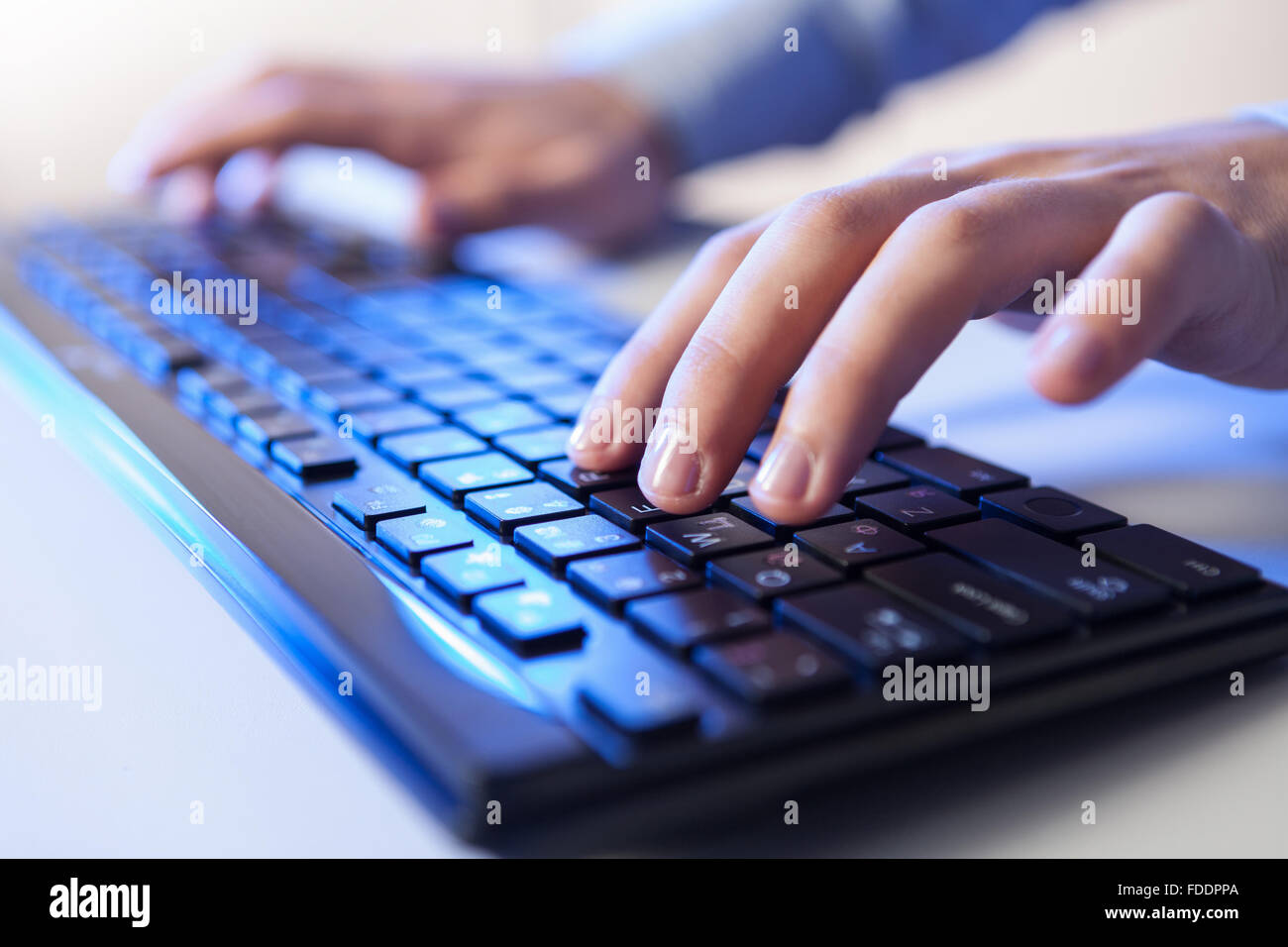 Click! Hands of a man on a keyboard with blue backlighting Stock Photo ...