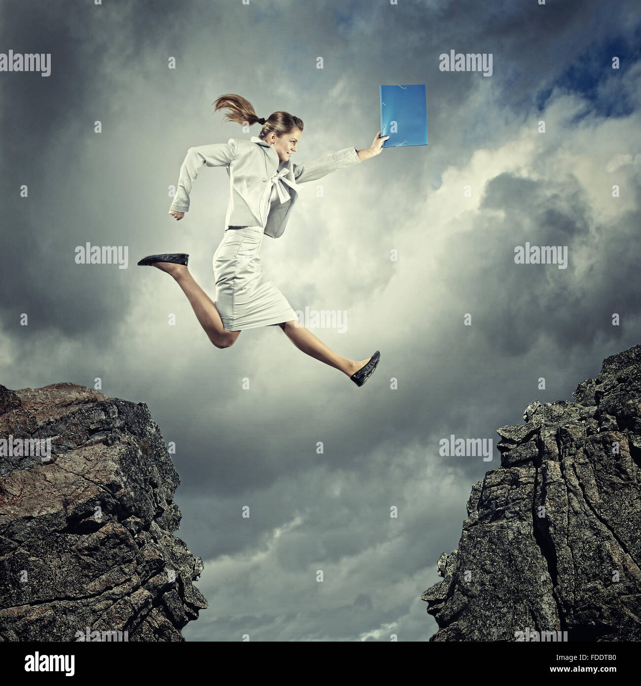 Image of young businesswoman jumping over gap Stock Photo - Alamy