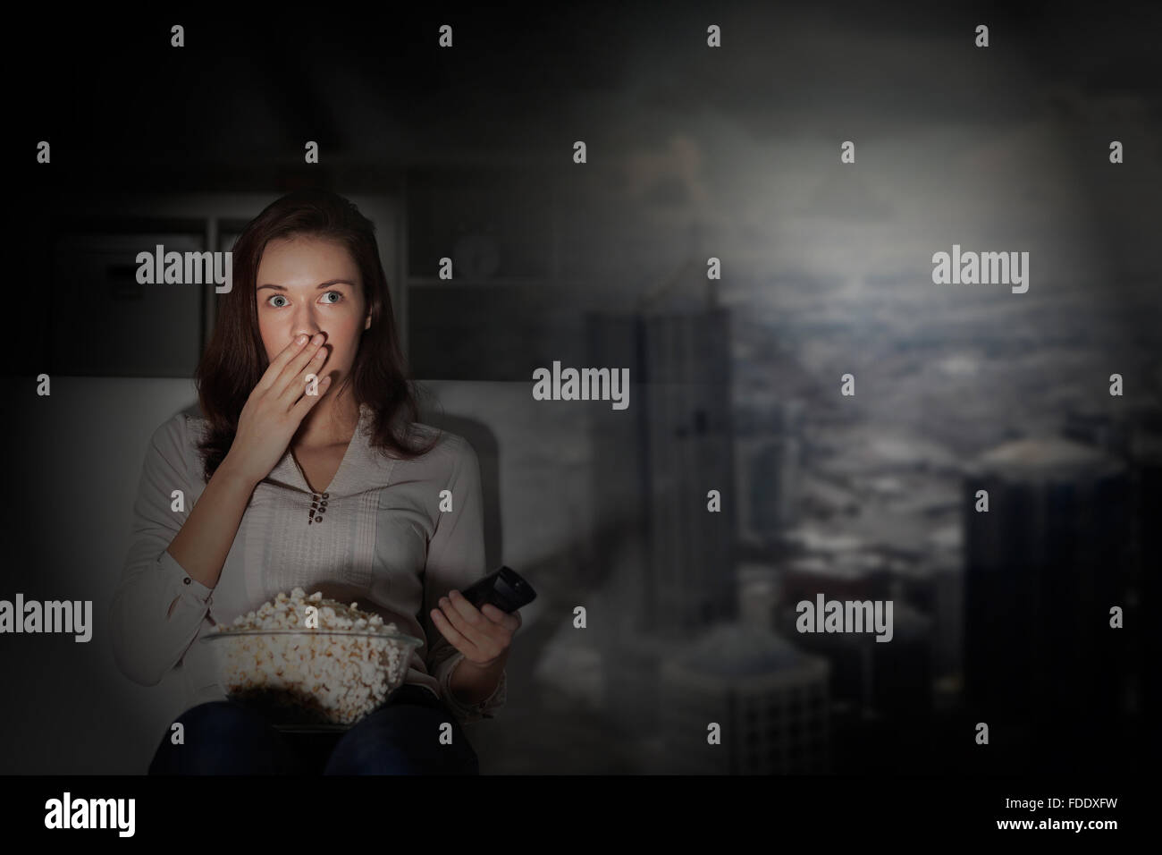 Scared young woman with click and popcorn watching TV Stock Photo - Alamy