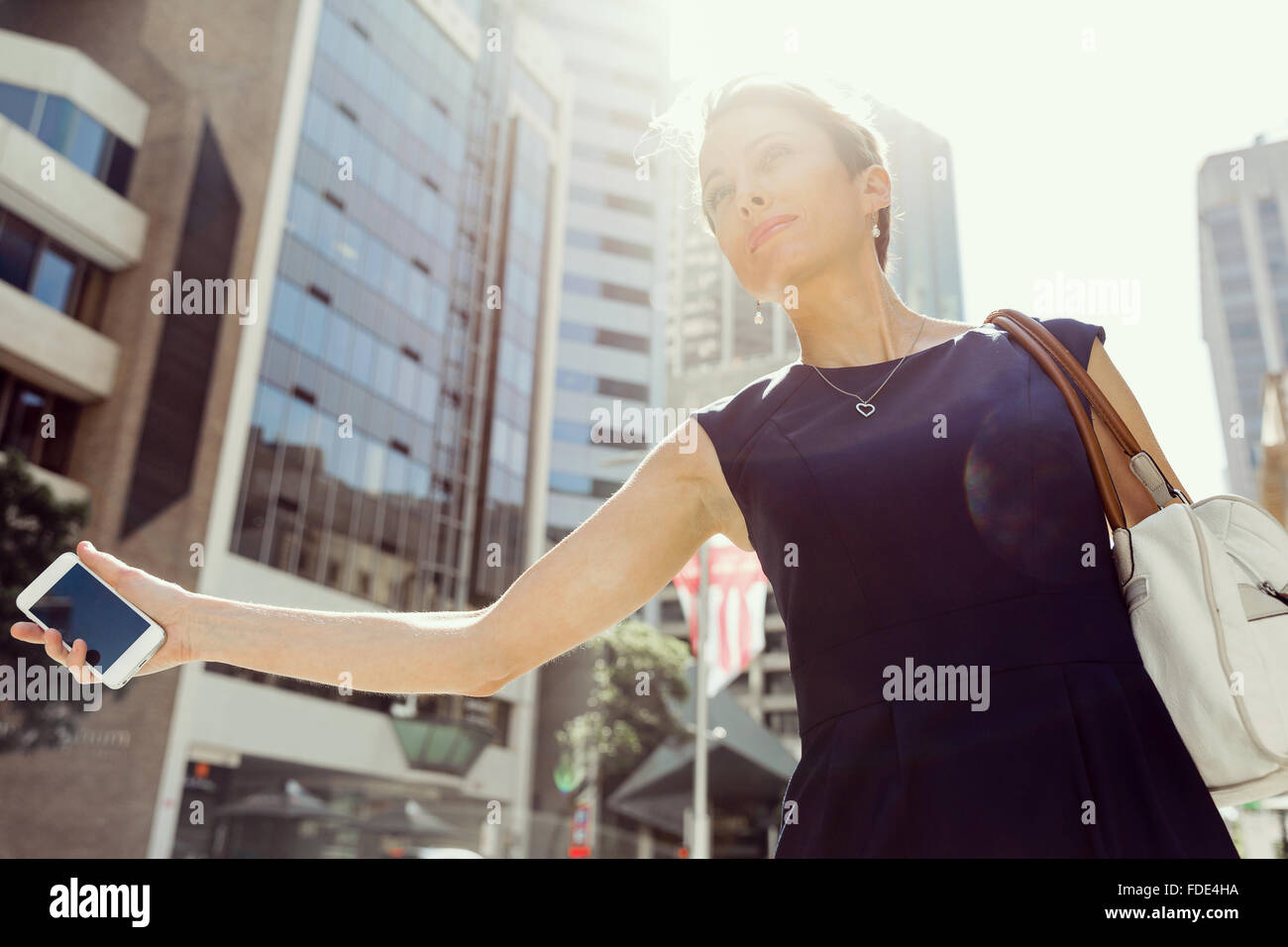 Businesswoman in a city street waving for taxi Stock Photo - Alamy