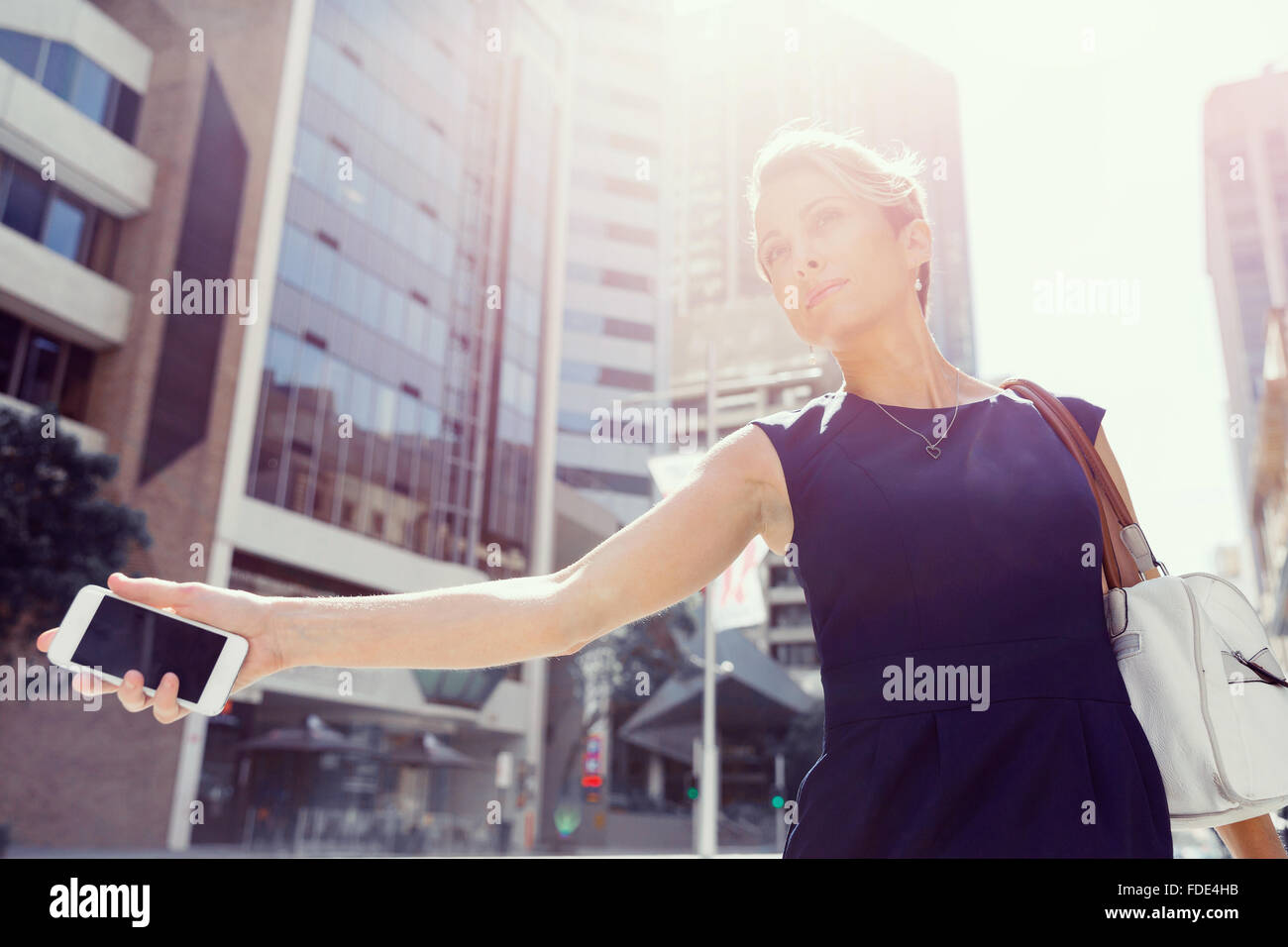 Businesswoman in a city street waving for taxi Stock Photo - Alamy