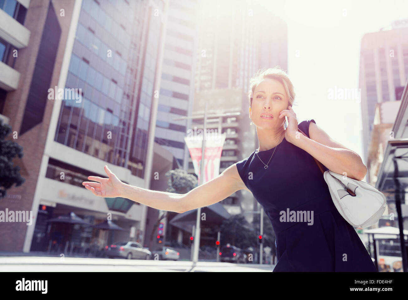 Businesswoman in a city street waving for taxi Stock Photo - Alamy