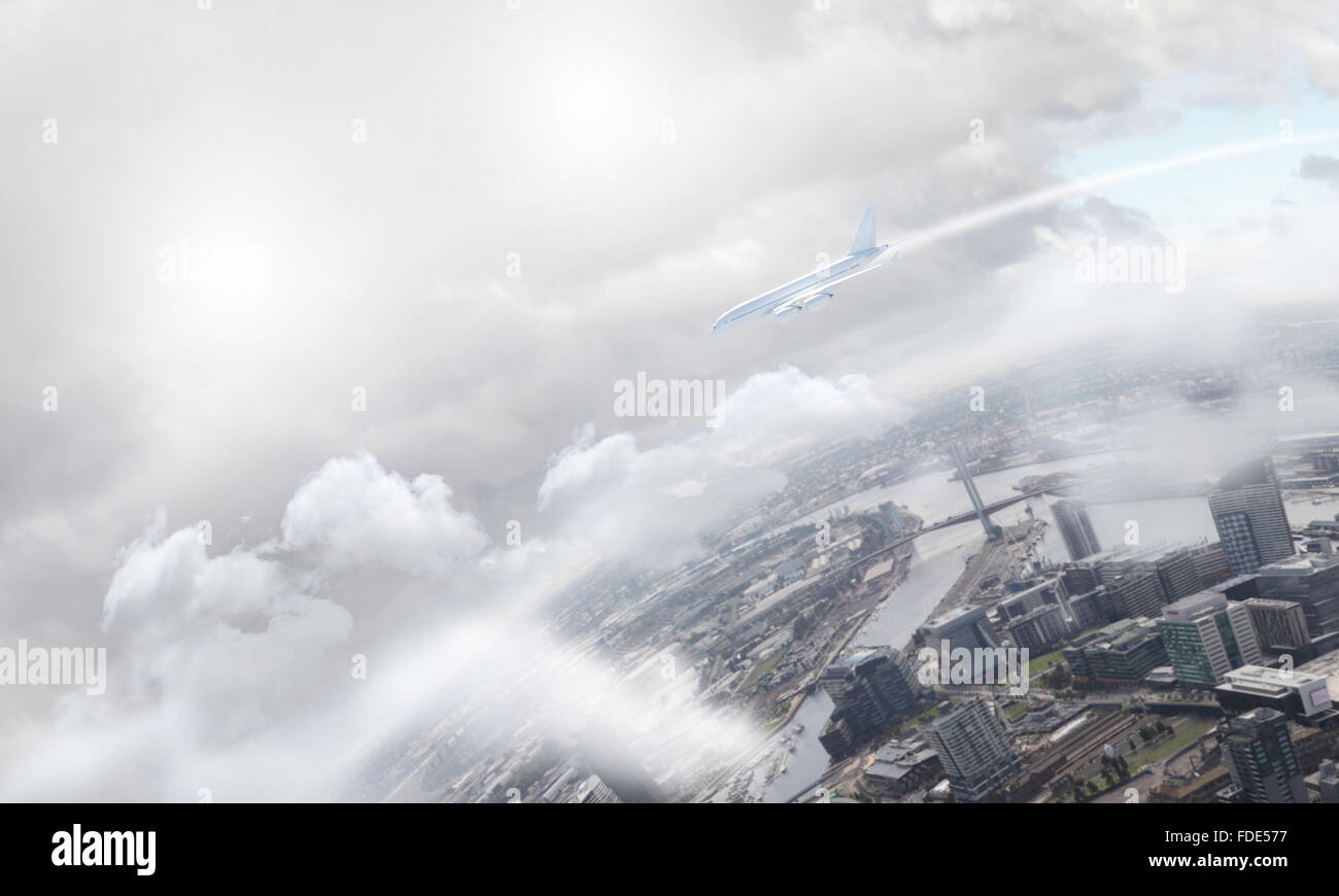 Airplane flying high in sky above city Stock Photo - Alamy