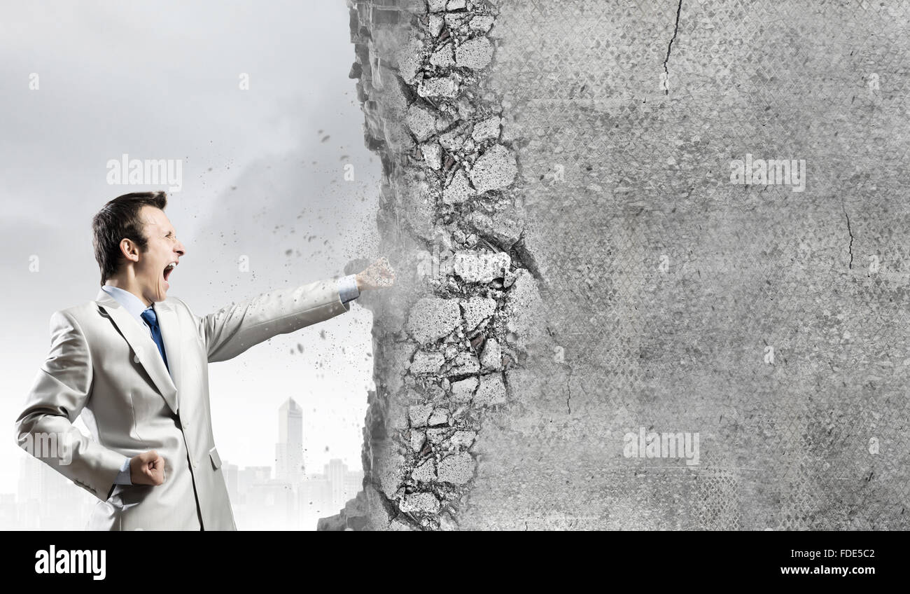 Businessman breaking stone wall with karate punch Stock Photo - Alamy