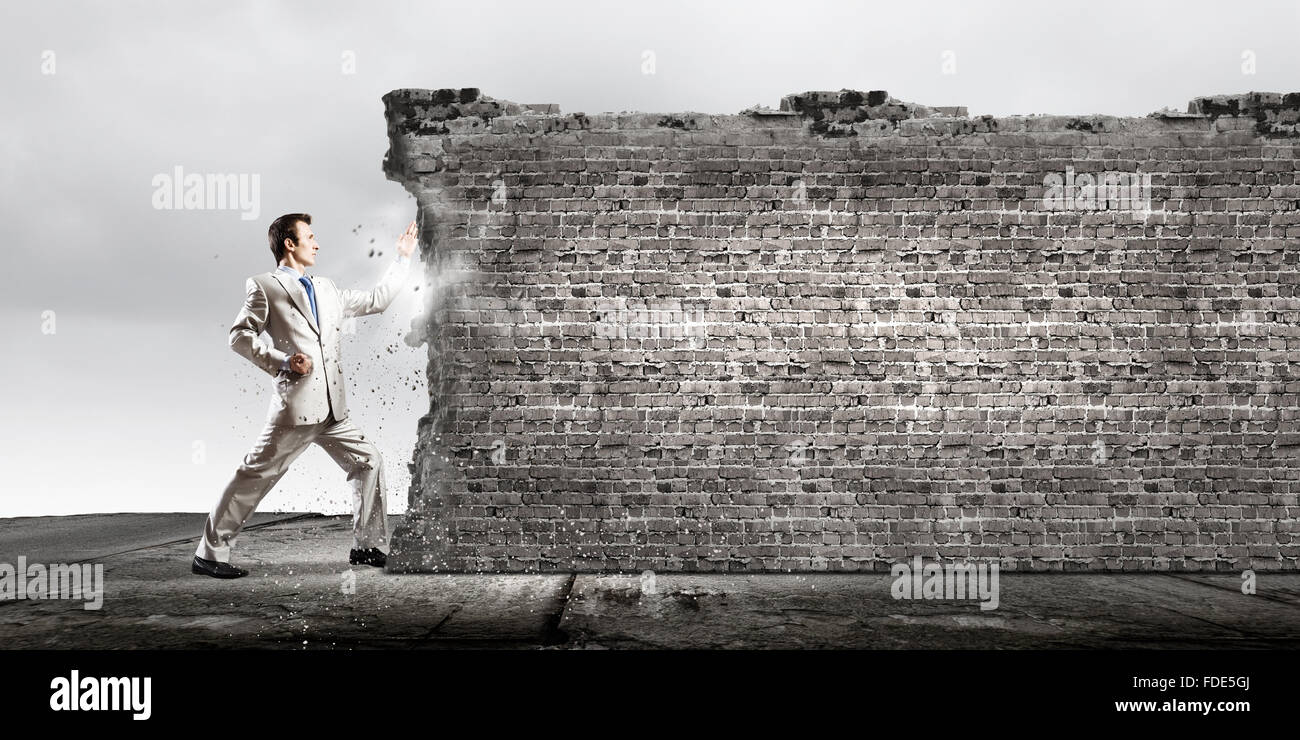Businessman breaking stone wall with karate kick hi-res stock ...