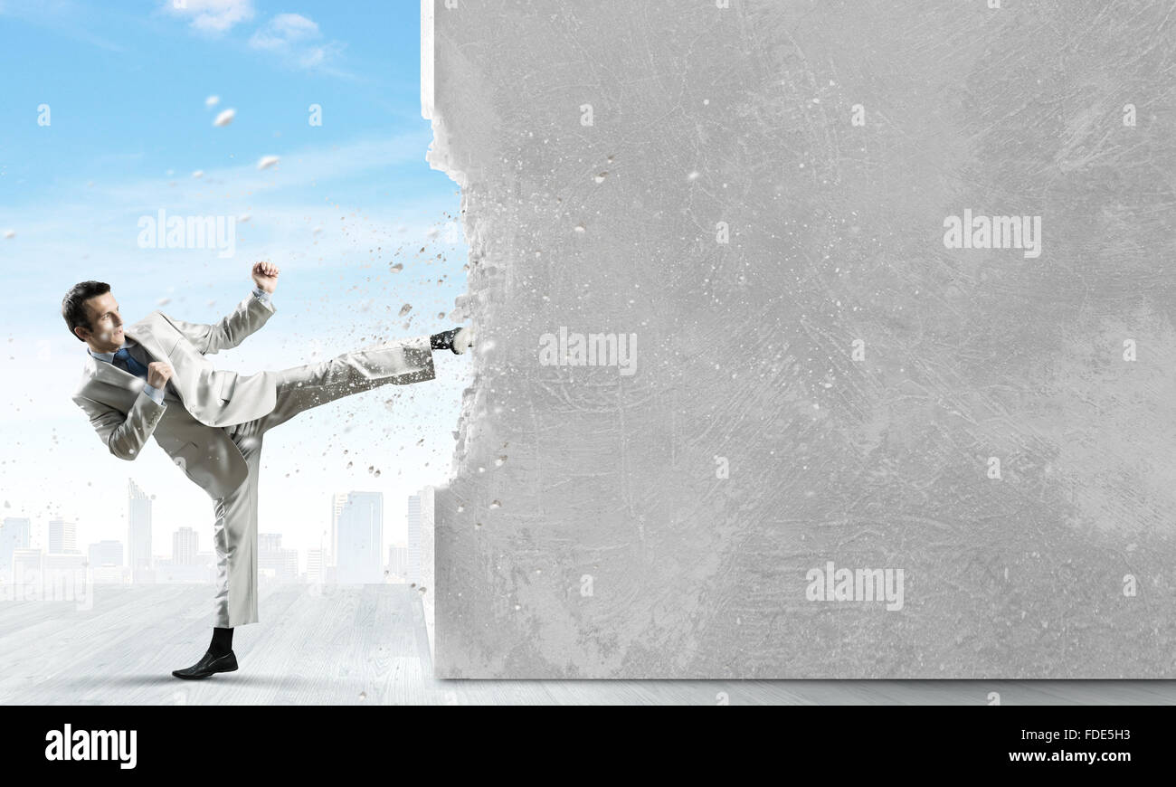 Businessman breaking stone wall with karate kick Stock Photo - Alamy