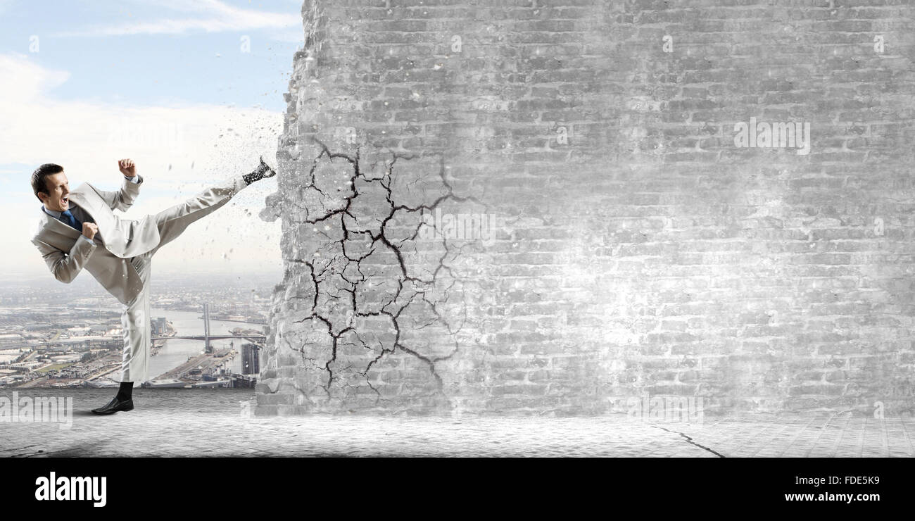 Businessman breaking stone wall with karate kick Stock Photo - Alamy