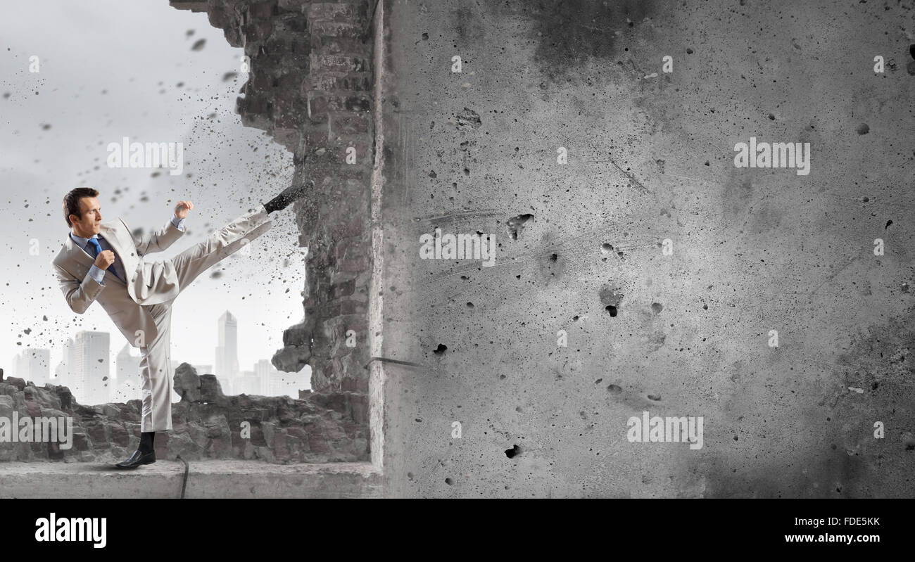 Businessman breaking stone wall with karate kick hi-res stock ...