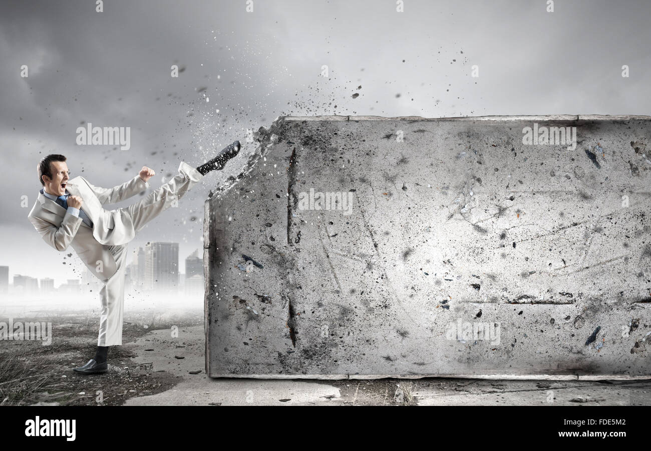 Businessman breaking stone wall with karate kick Stock Photo - Alamy