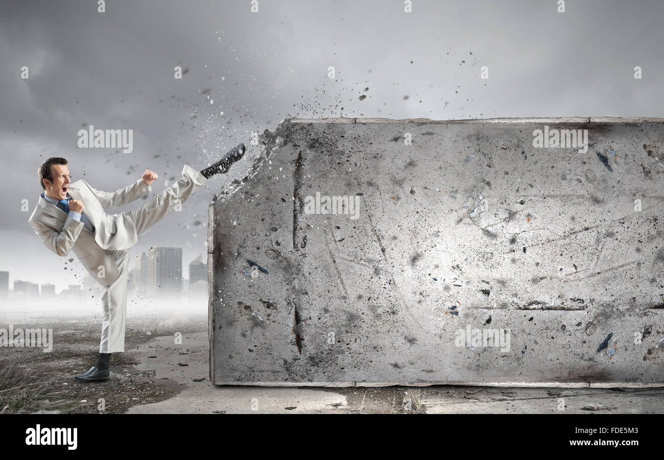 Businessman breaking stone wall with karate kick Stock Photo - Alamy