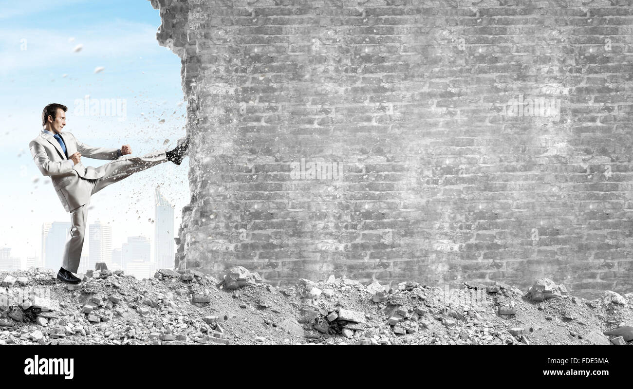Businessman breaking stone wall with karate kick Stock Photo - Alamy