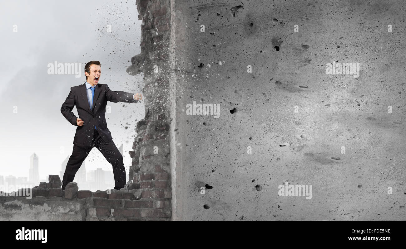 Businessman breaking stone wall with karate punch Stock Photo - Alamy