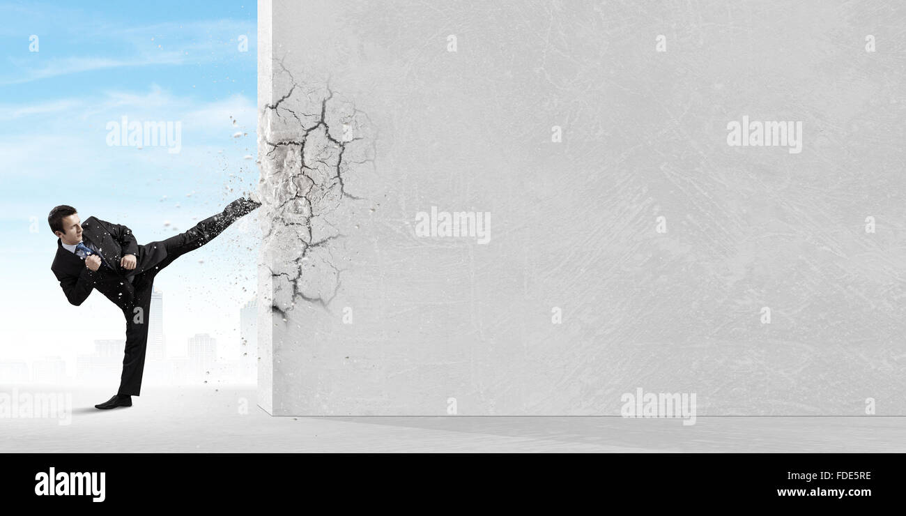 Businessman breaking stone wall with karate kick Stock Photo - Alamy