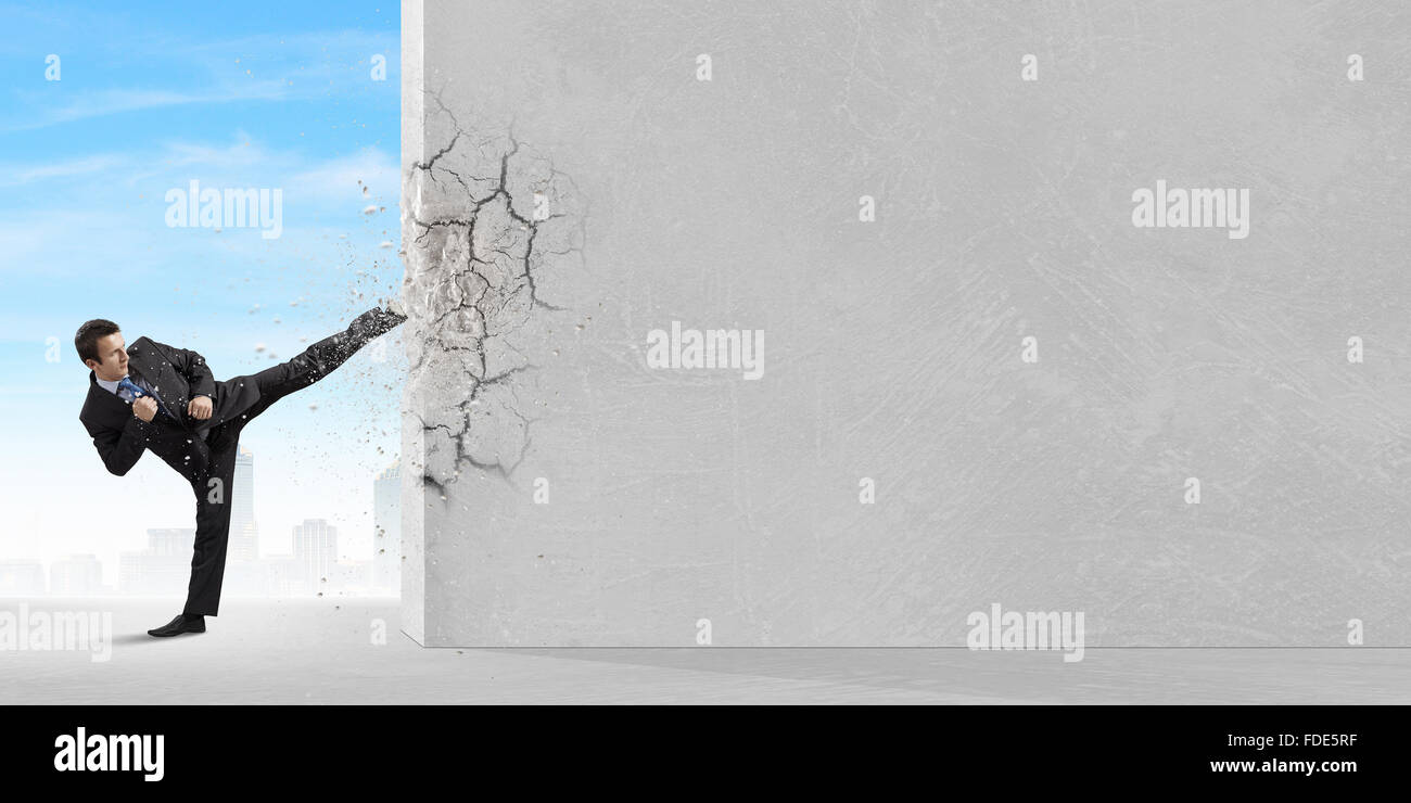 Businessman breaking stone wall with karate kick Stock Photo - Alamy
