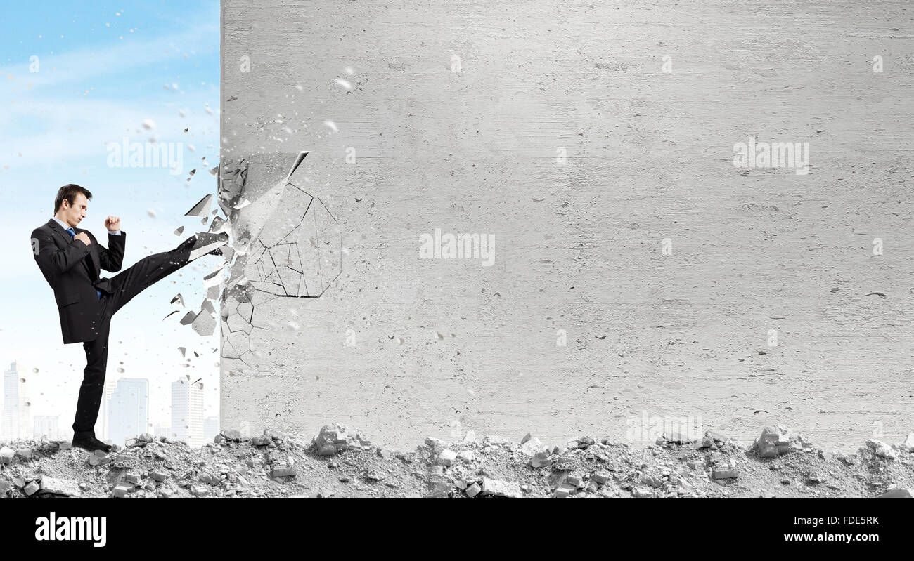 Businessman breaking stone wall with karate kick Stock Photo - Alamy