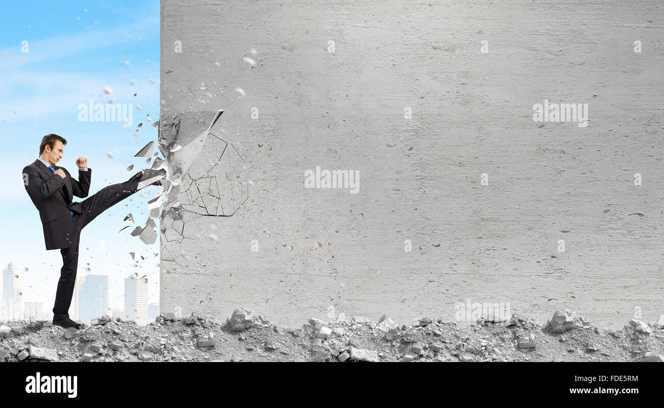 Businessman breaking stone wall with karate kick Stock Photo - Alamy