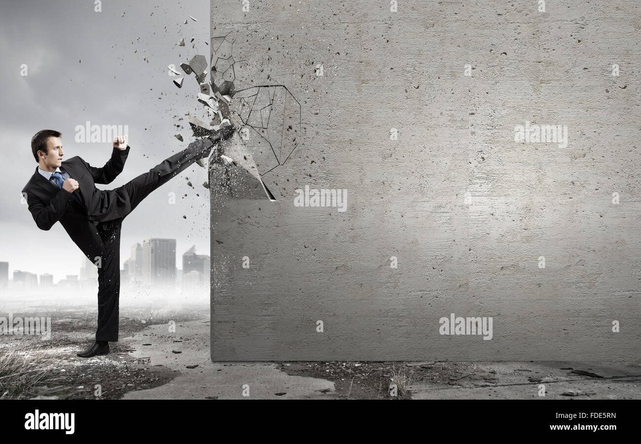 Businessman breaking stone wall with karate kick Stock Photo - Alamy