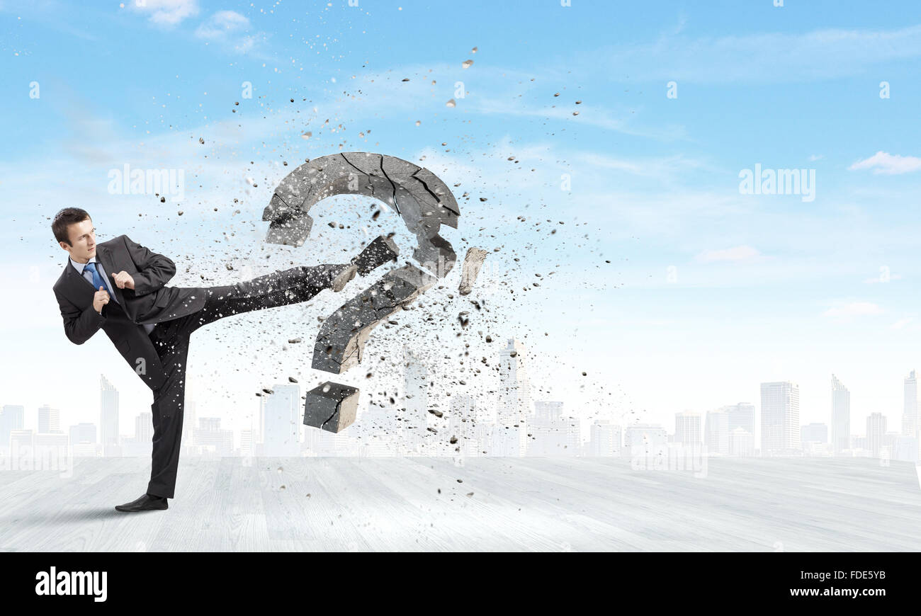 Businessman breaking stone question mark with karate kick Stock Photo ...