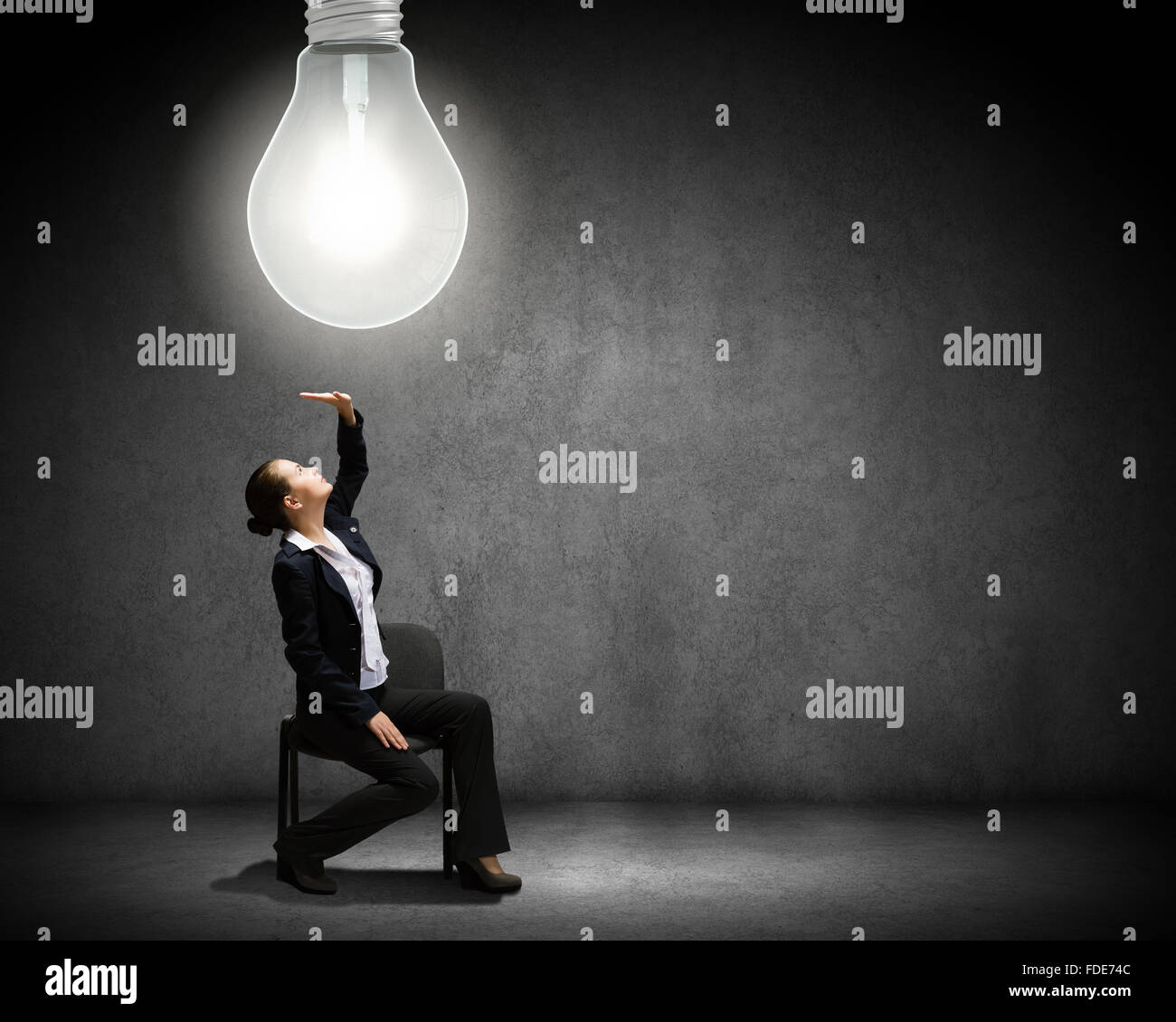 Young businesswoman sitting on chair with big light bulb above Stock ...