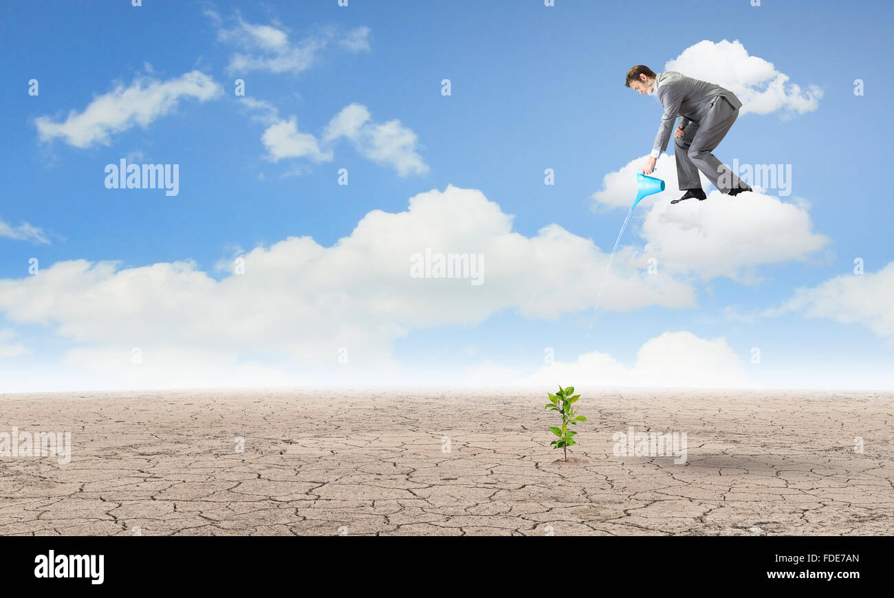 Young businessman standing on cloud and watering sprout Stock Photo - Alamy