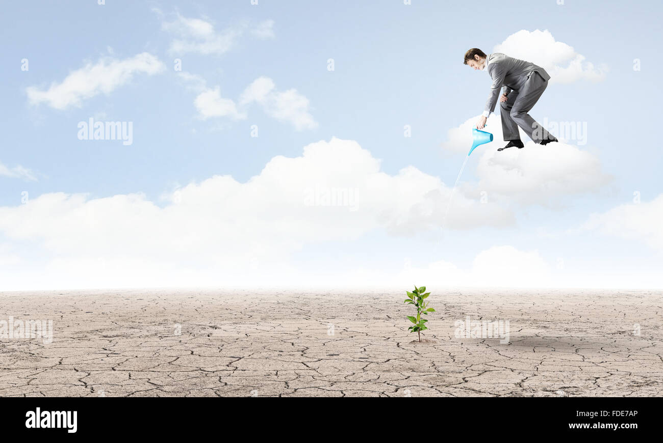 Young businessman standing on cloud and watering sprout Stock Photo - Alamy