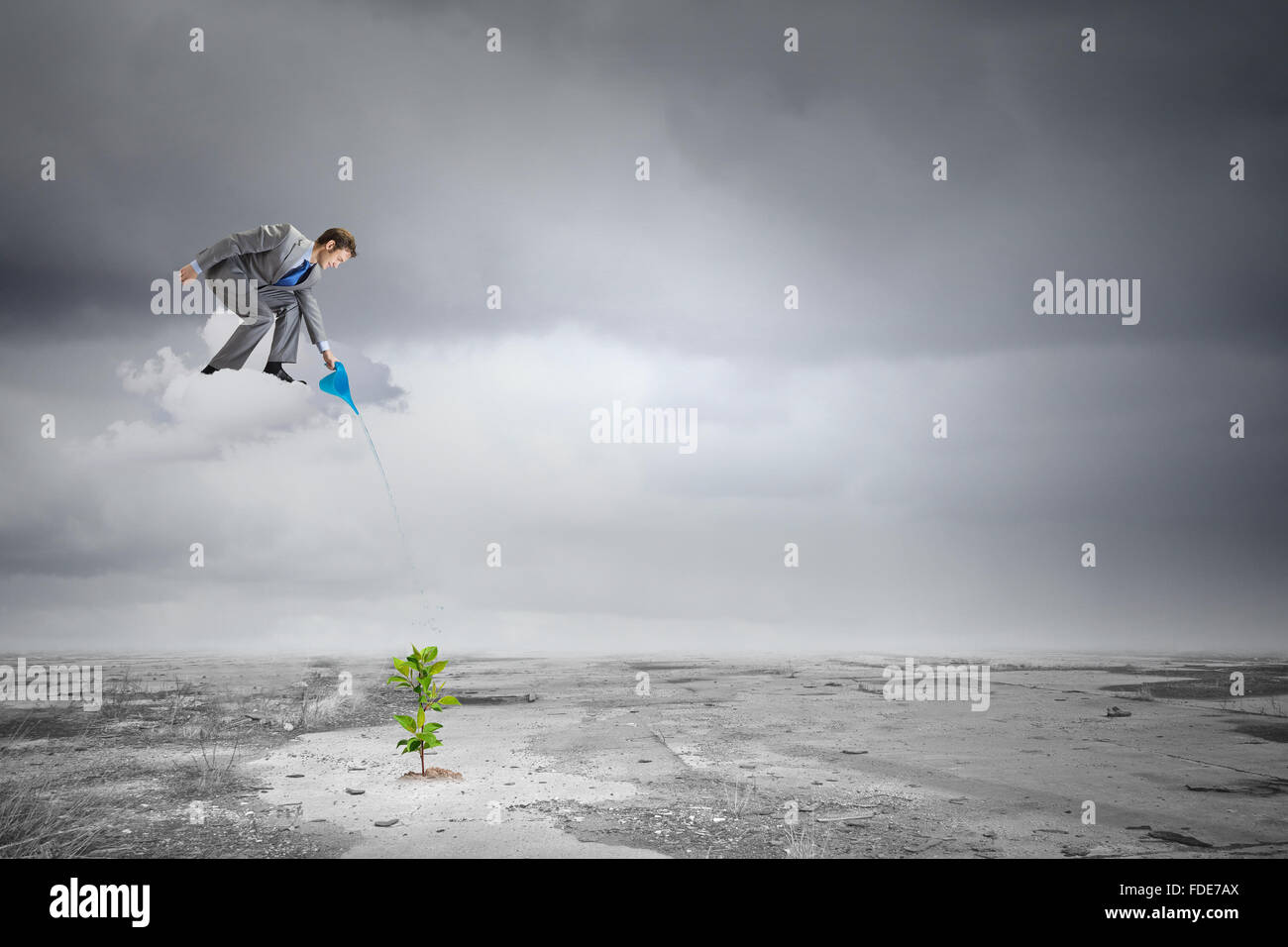 Young businessman standing on cloud and watering sprout Stock Photo - Alamy