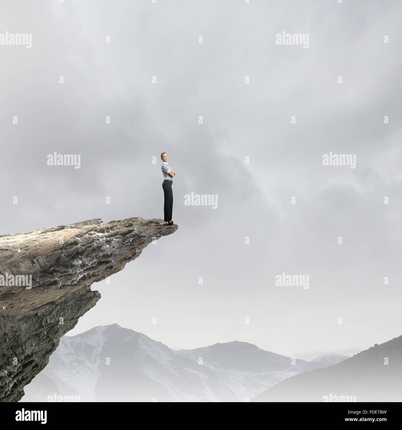 Attractive businesswoman standing on edge of mountain Stock Photo - Alamy