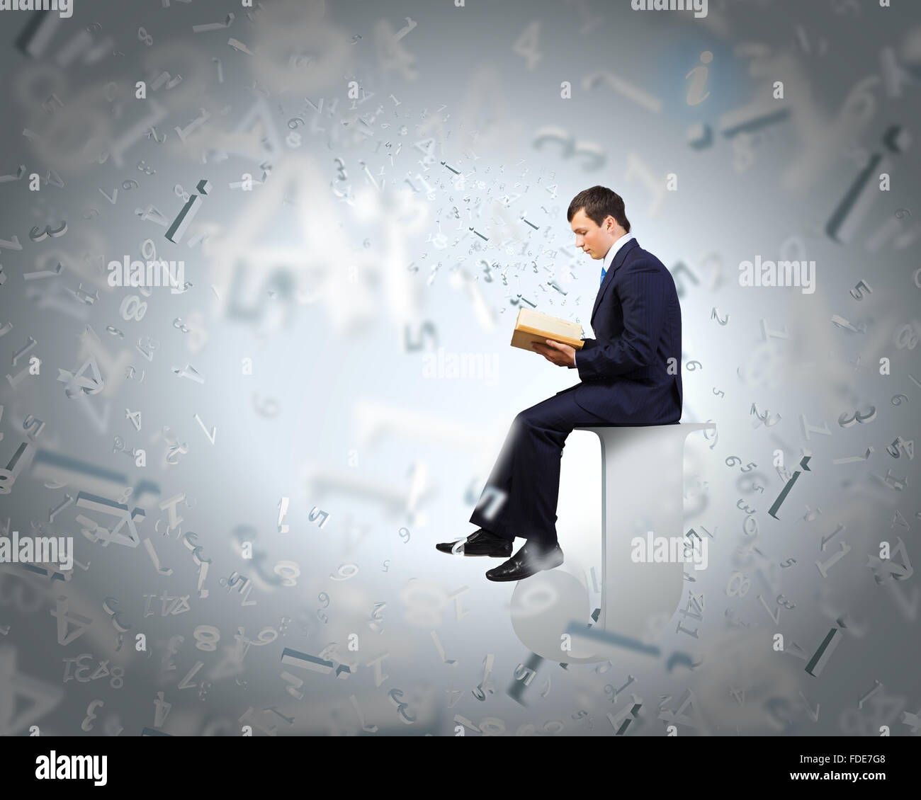 Young businessman sitting on letter and reading book Stock Photo - Alamy