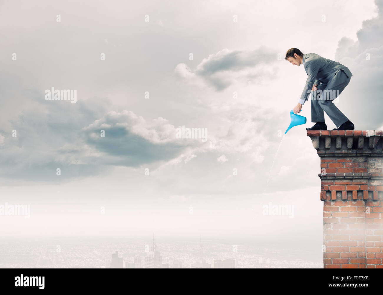 Young businessman standing on cloud and watering something below Stock ...