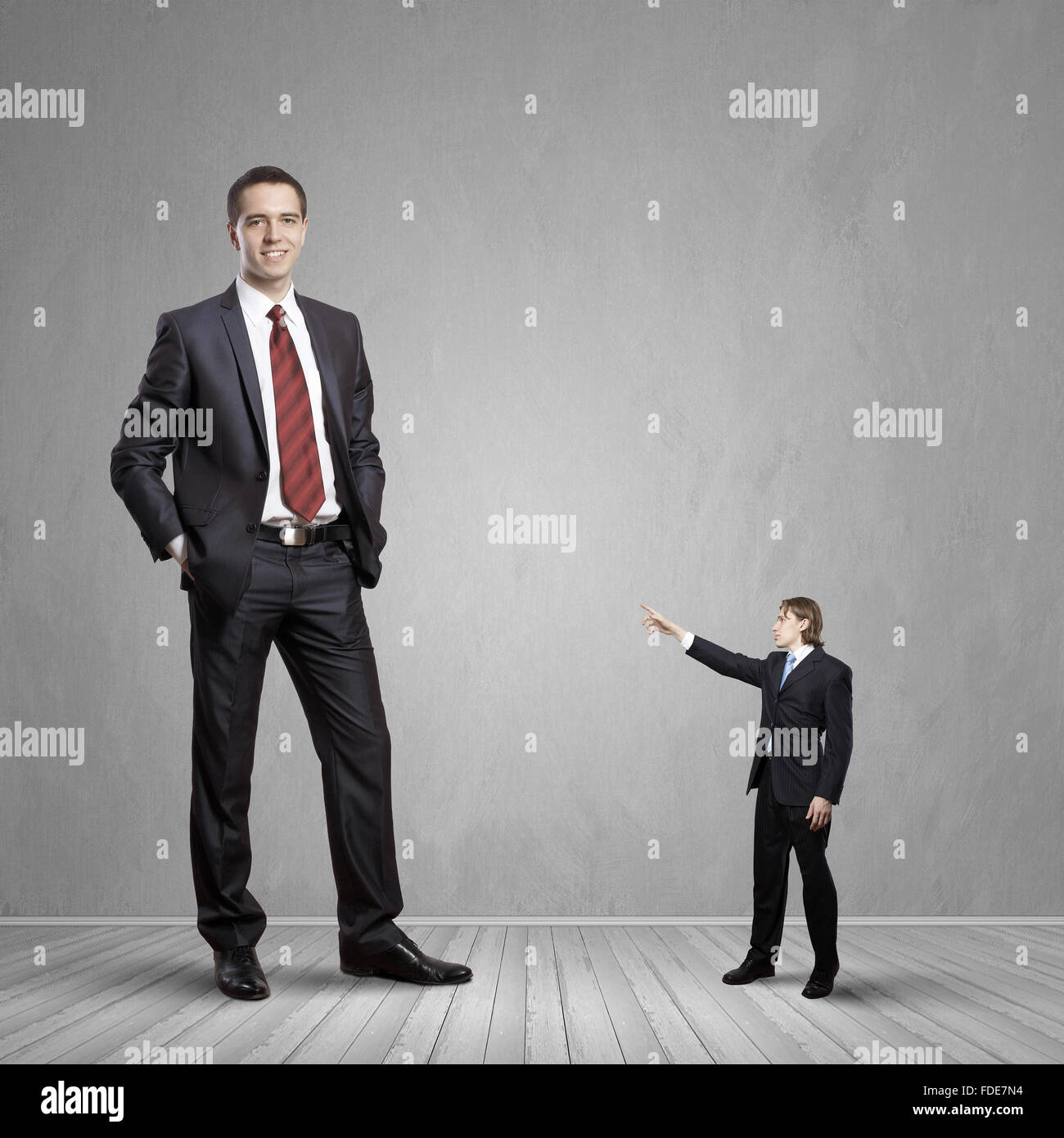 Big bossy businessman looking down at small businessman Stock Photo - Alamy