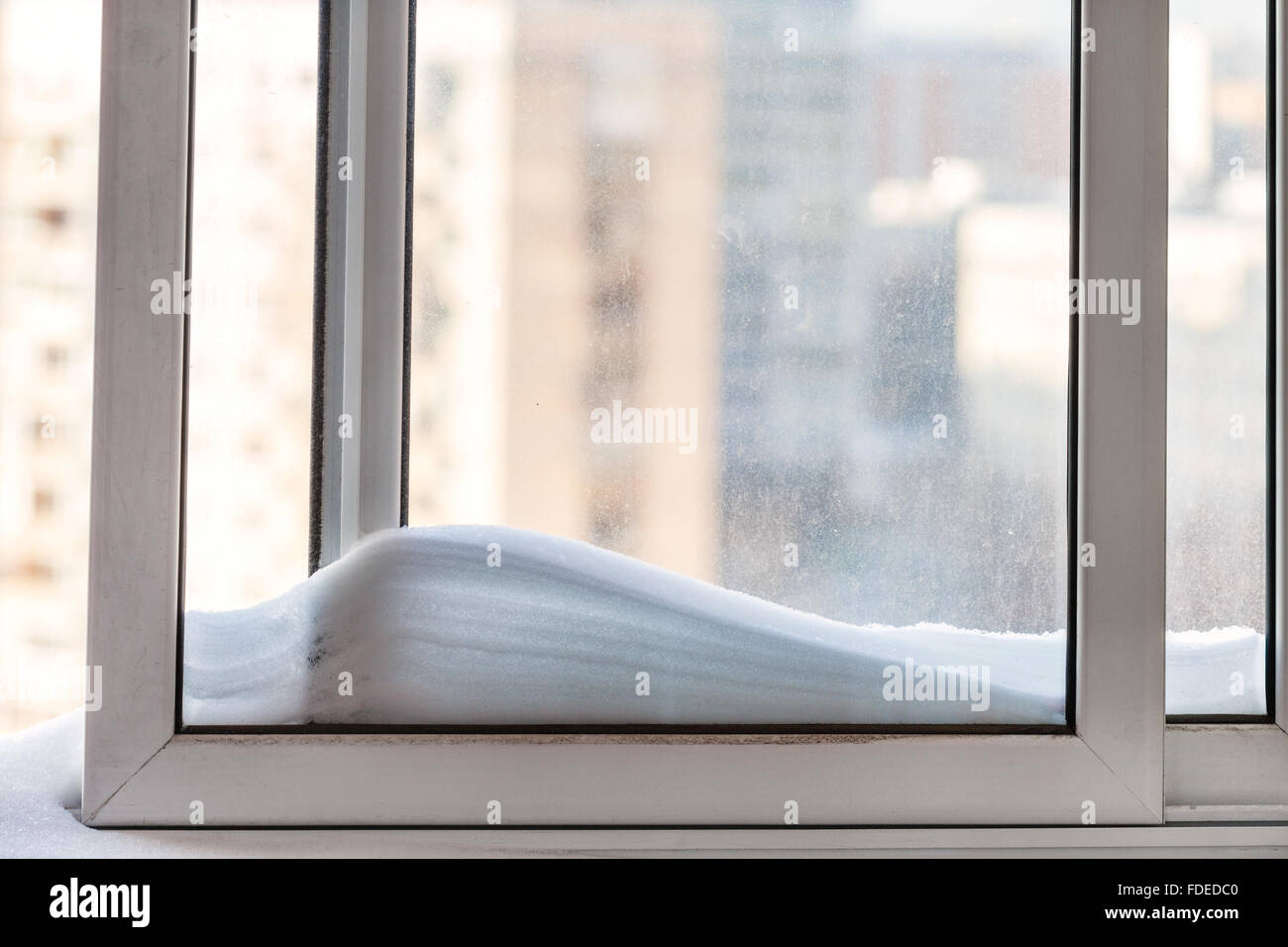 snowdrift on window casement and cityscape on background in sunny ...