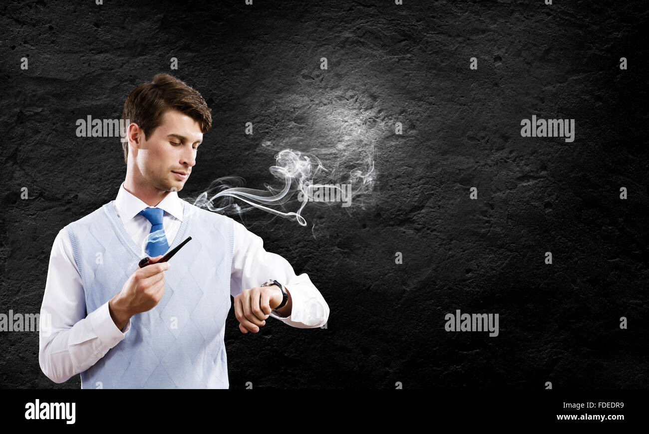 Young handsome businessman smoking pipe against black background Stock ...