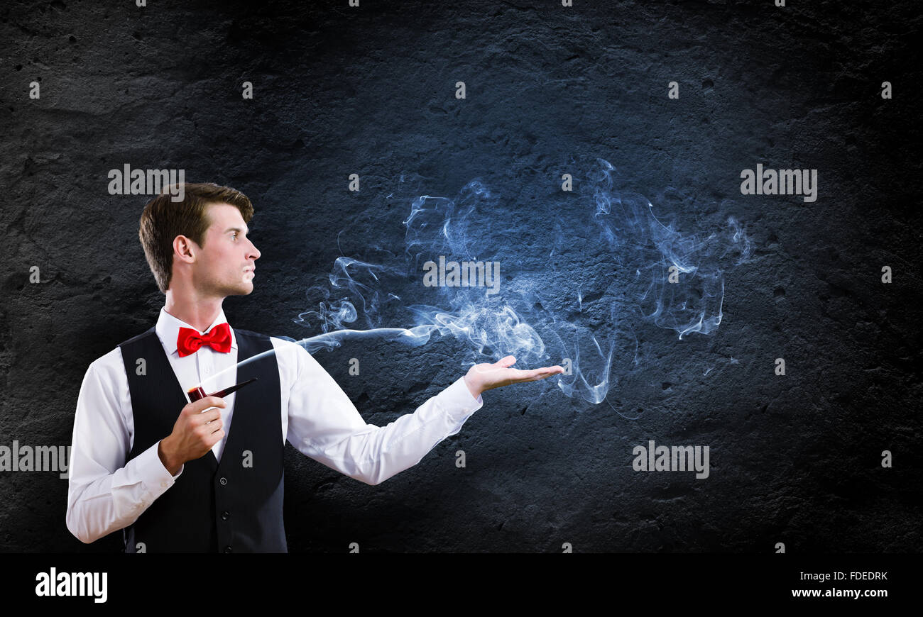 Young handsome businessman smoking pipe against black background Stock ...