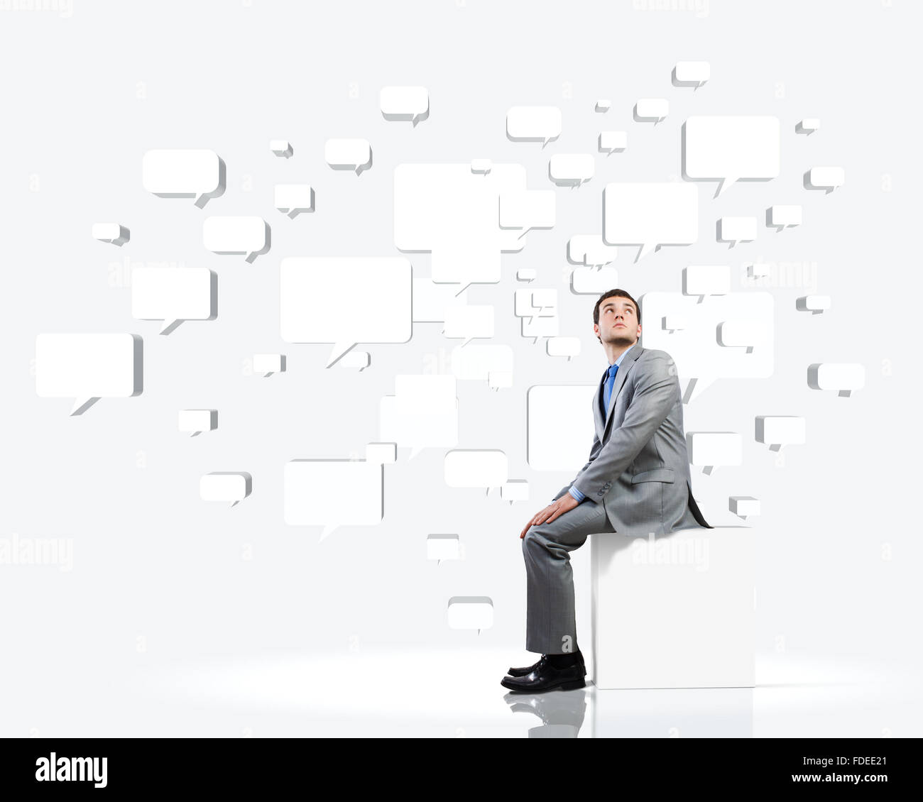 Young handsome businessman sitting on white cube Stock Photo - Alamy