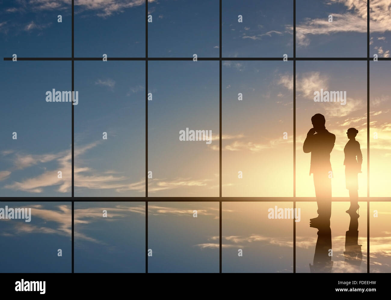 Silhouettes of businesspeople standing against panoramic office window ...