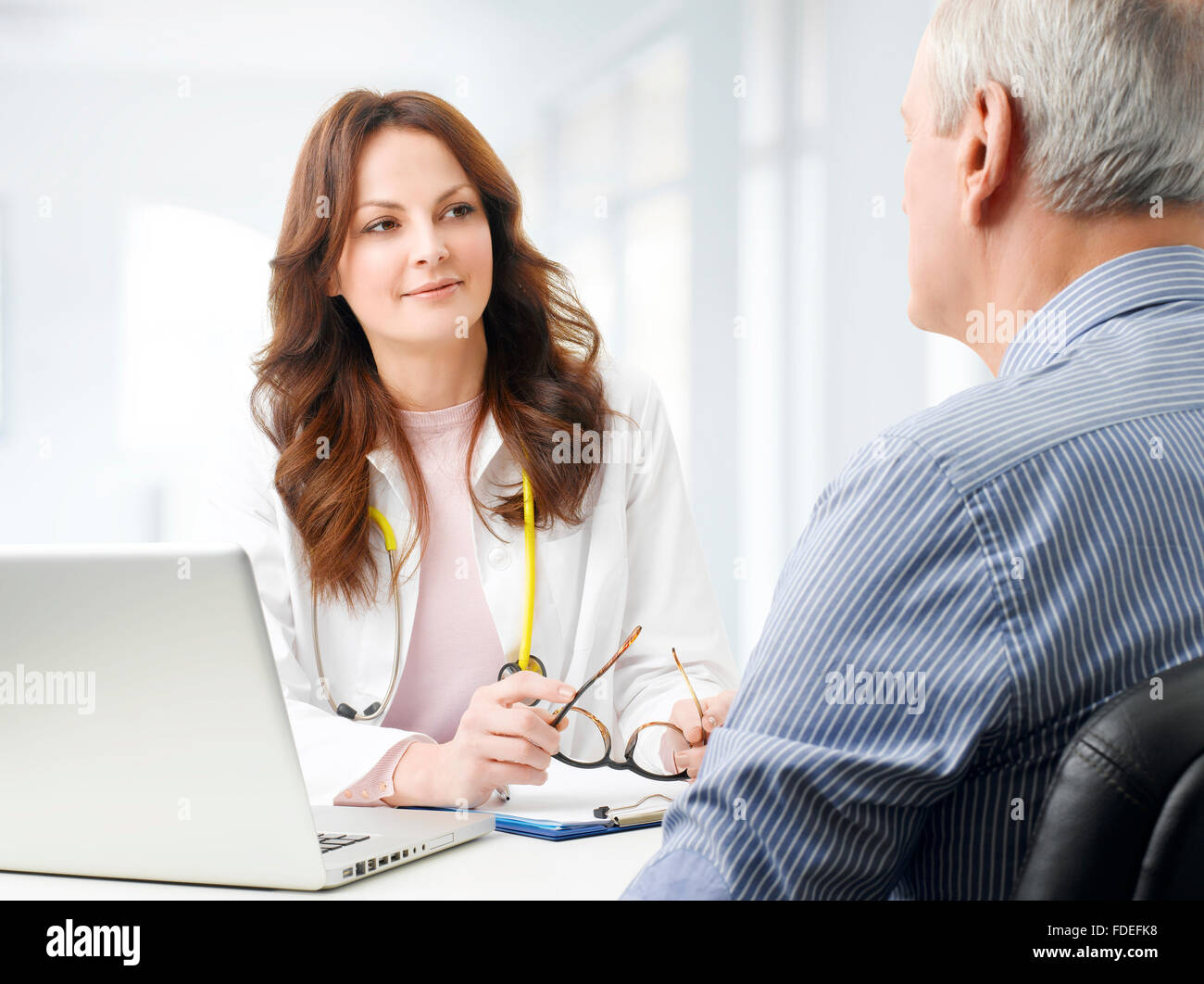 Portrait of femael doctor sitting at desk in front of computer and ...