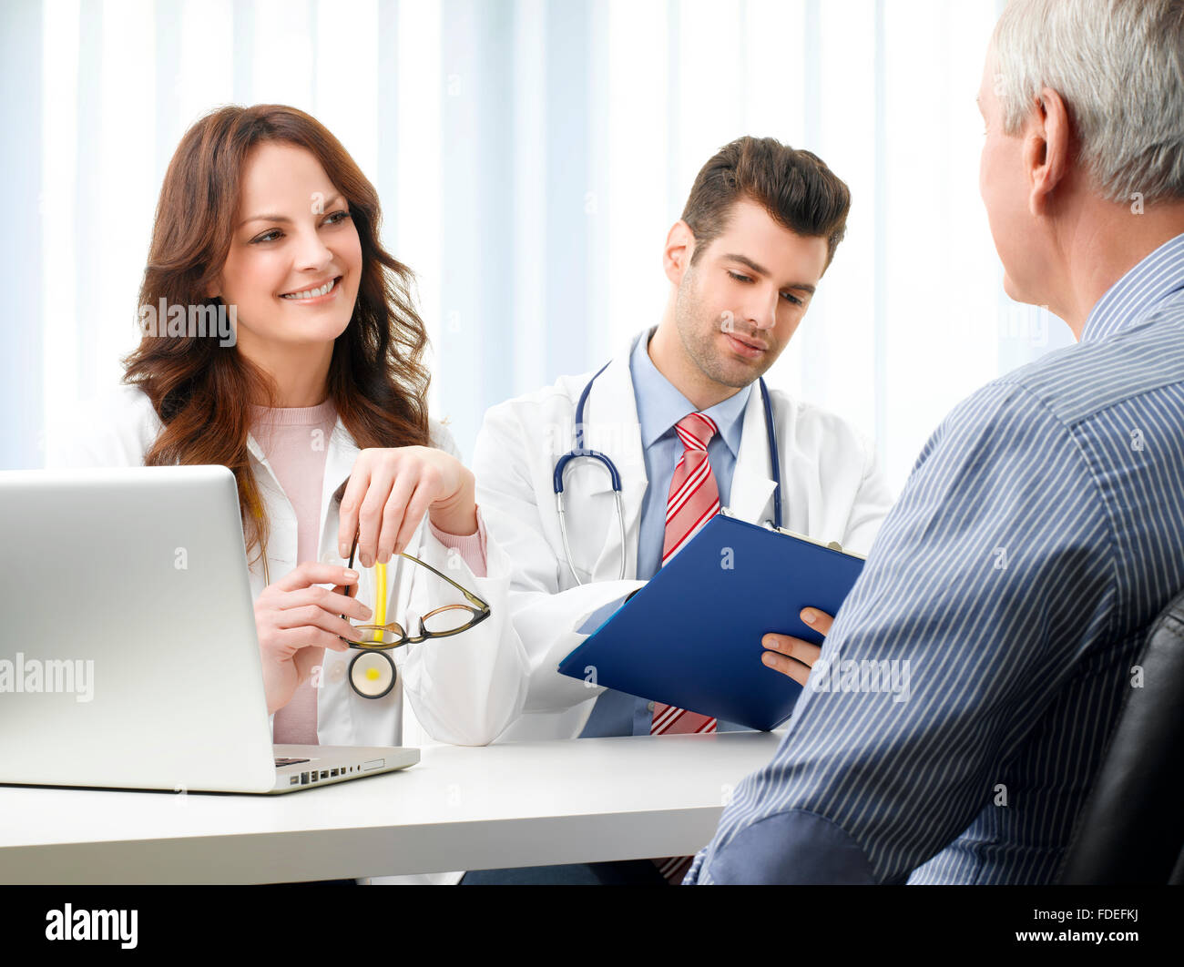 Medical team consulting with old patient at private clinic Stock Photo ...